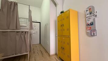 Quarto de dormitório com beliches, piso de madeira e um móvel de armazenamento amarelo com armários.