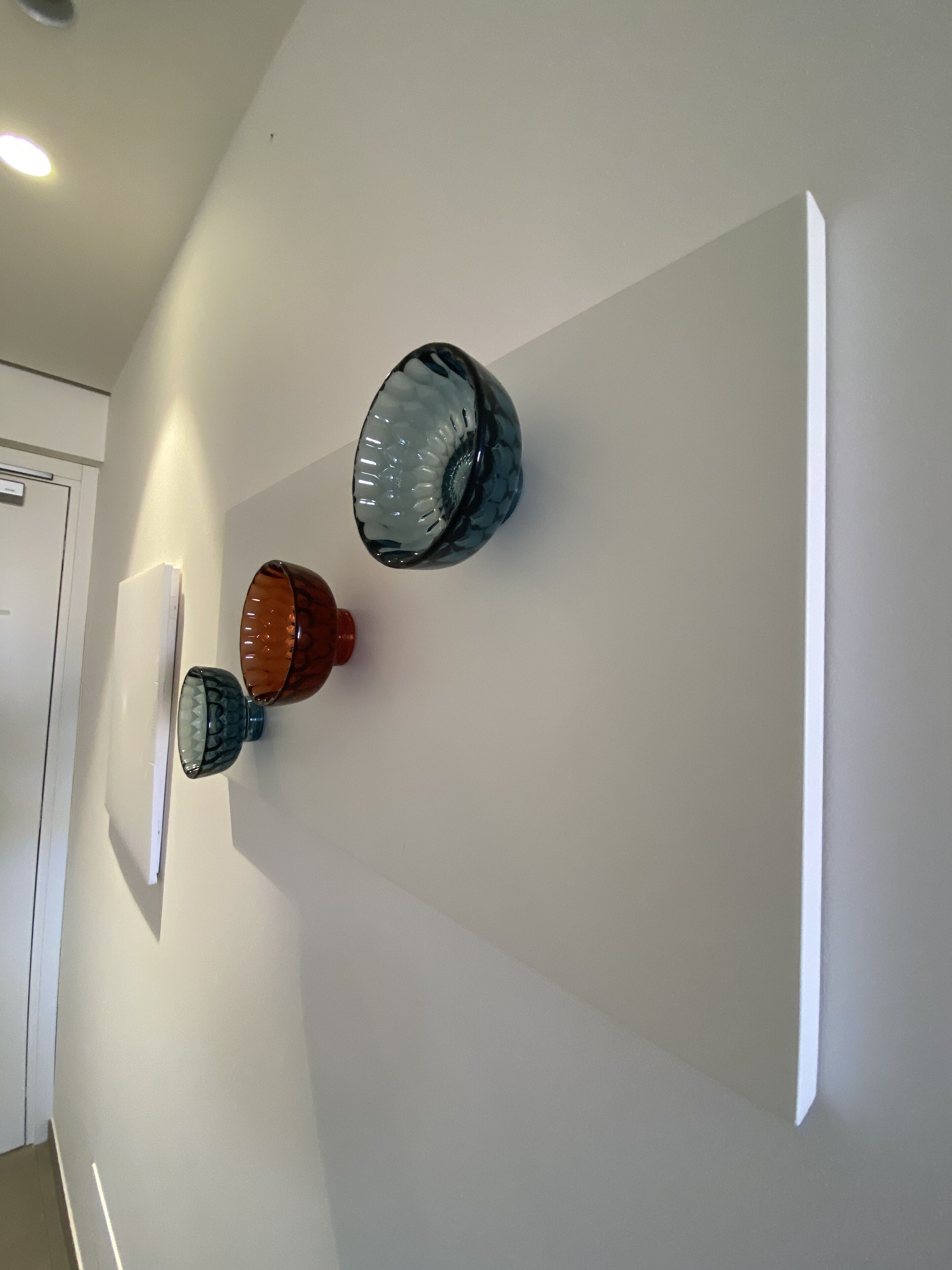 Arranjo de luz fixado na parede, com base retangular e topo curvo, semelhante a vidro.