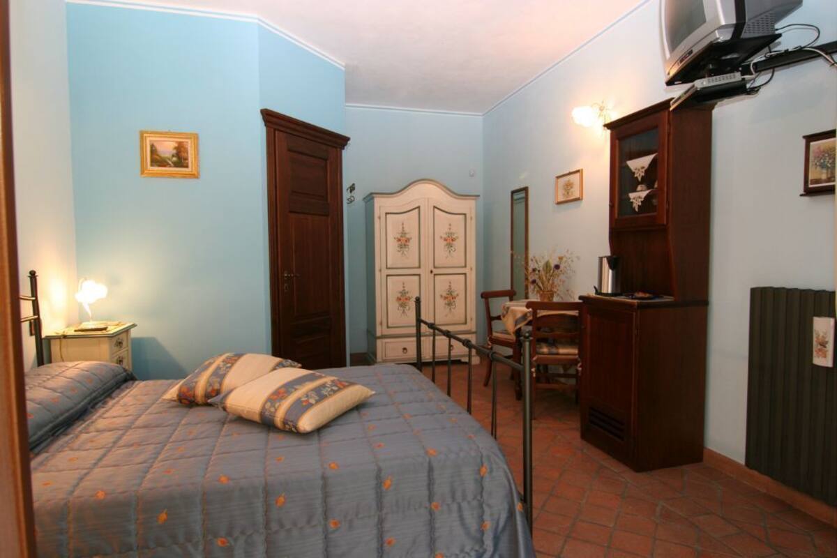 Quarto com cama, cômoda e televisão.