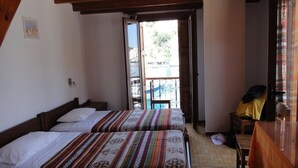 Quarto com duas camas, teto de madeira, uma mesinha e vista para uma varanda.