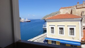 Vista costeira com um edifício com telhado de telhas vermelhas e varanda com vista para o mar.