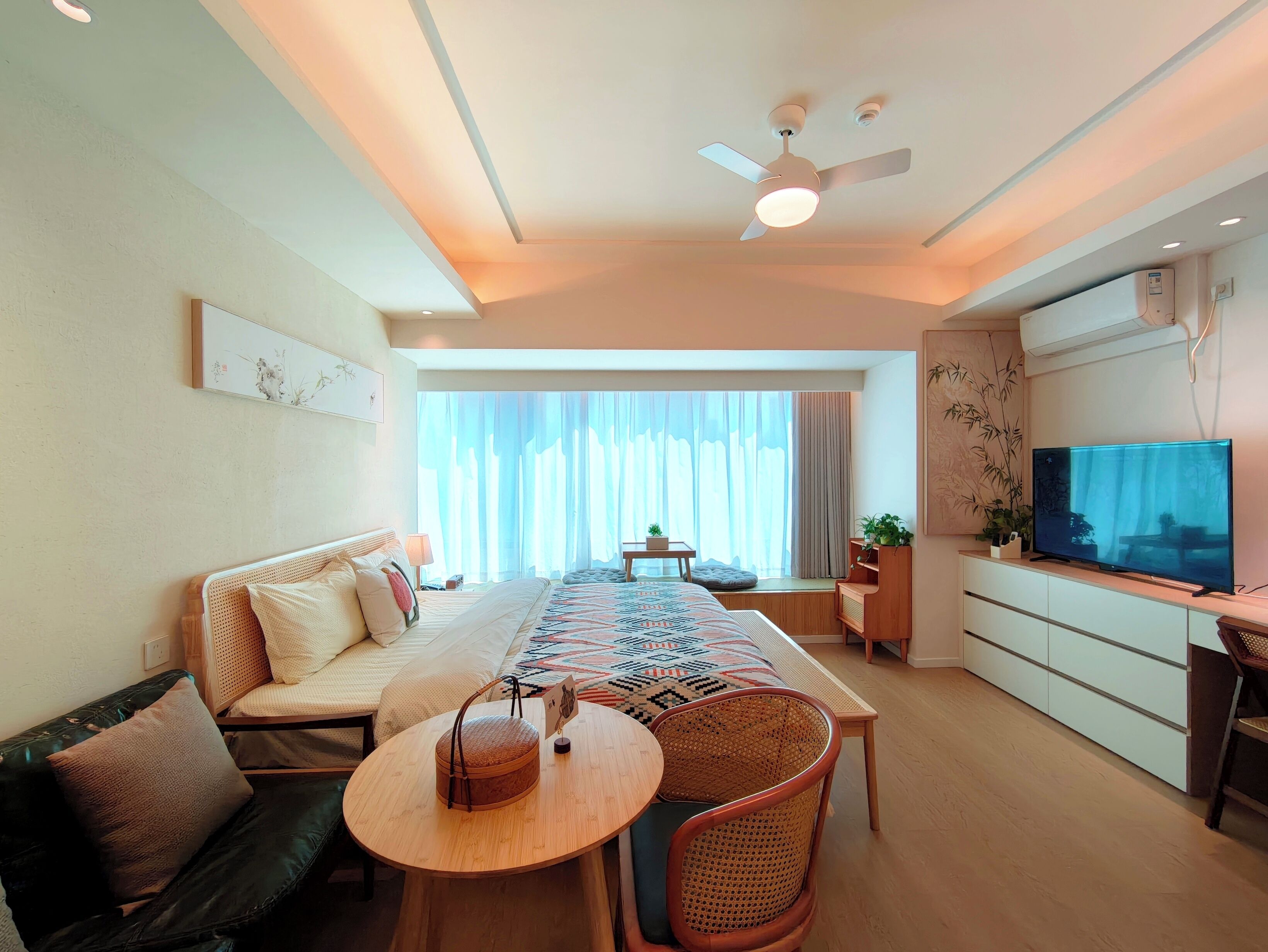 Uma sala de estar moderna com sofá, mesa de jantar, televisão e ventoinha no teto.