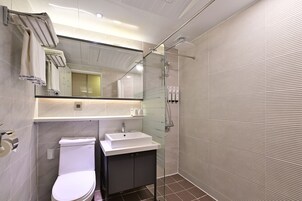 Uma casa de banho moderna com sanita, lavatório e chuveiro.