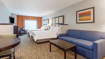 Quarto de hotel com uma cama grande, sofá, escrivaninha e cadeira.