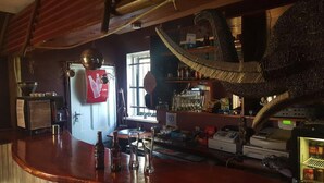 Uma área de bar com balcão, garrafas, copos e caixa registradora.