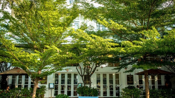Um edifício com grandes janelas, área de estar coberta ao ar livre e um jardim bem cuidado.