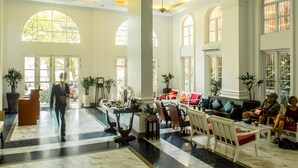 Um hall amplo com piso de mármore, grandes janelas em arco e um balcão de recepção.