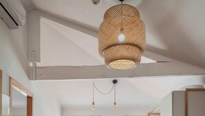 Uma área de refeições com uma mesa e cadeiras, um lustre pendurado e uma janela com persianas.