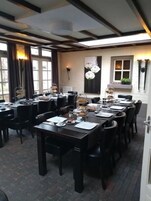 Sala de conferência com várias mesas preparadas para reuniões, equipada com cadeiras e uma grande janela que proporciona iluminação natural.