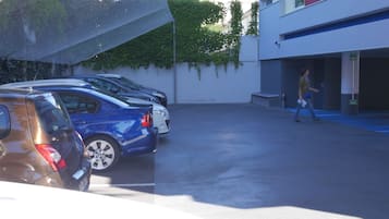 Um espaço de estacionamento com vários carros e uma pessoa caminhando.