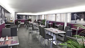 Restaurante moderno com layout clean, apresentando várias mesas e cadeiras, janelas amplas com persianas e um mural na parede.