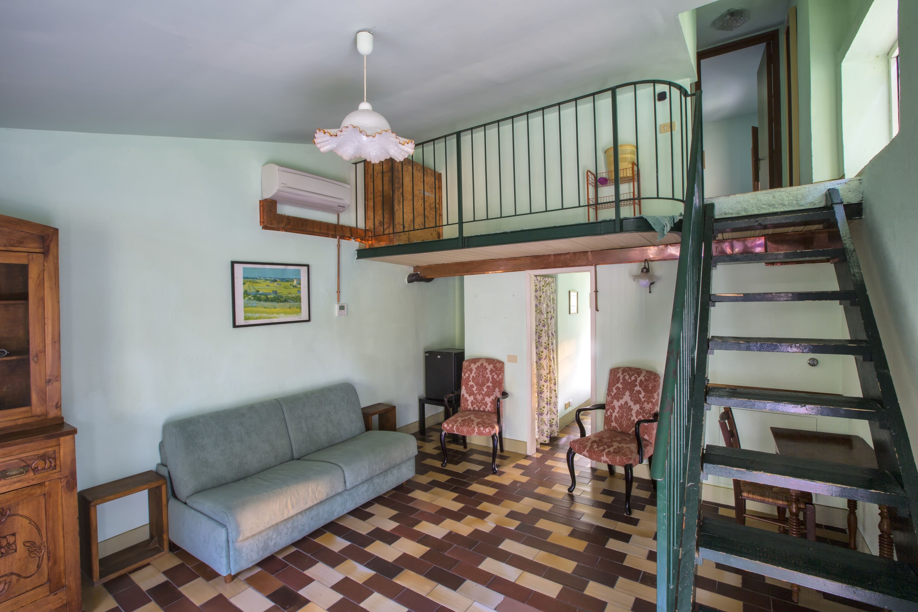 Uma sala de estar com sofá, cadeiras estampadas, escada e um armário de madeira.