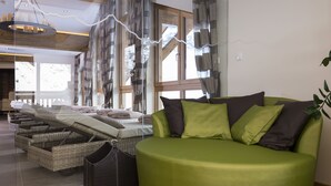 Uma sala de estar moderna com sofá verde, móveis de vime e grandes janelas.