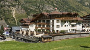 Hotel com várias varandas, área de estar externa e vista para uma paisagem montanhosa.