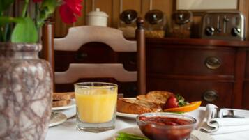 Uma mesa de café da manhã com torradas, frutas e um copo de suco de laranja.