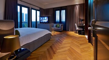 Quarto de hotel com uma cama grande, uma escrivaninha, uma cadeira e uma televisão.