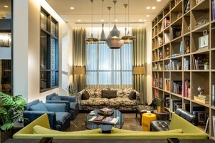 Uma sala de estar moderna com um sofá estampado, uma mesa de centro e uma estante repleta de livros.