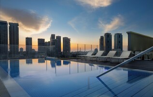 Uma piscina infinita no terraço, com vista para o horizonte urbano, cadeiras de descanso e um design arquitetônico moderno.