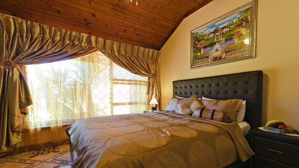 Um quarto com uma cama grande, teto de madeira e um quadro na parede.