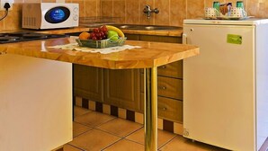 Uma cozinha compacta com armários de madeira, micro-ondas, geladeira e uma pequena mesa de jantar.
