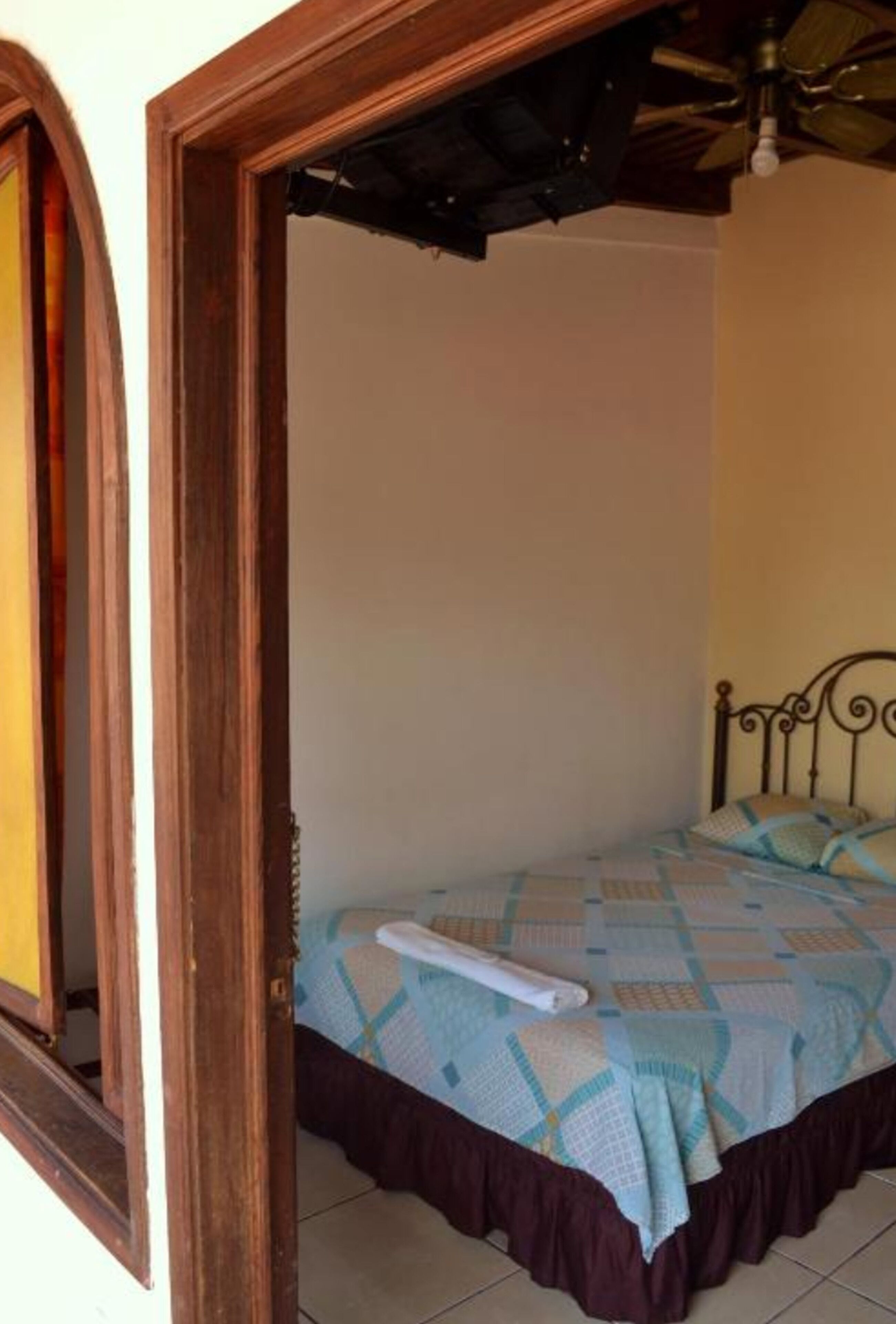 Quarto com cama, moldura de porta de madeira e ventilador de teto.