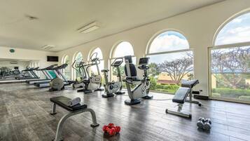 Academia com aparelhos de cardio, pesos livres e bancos.