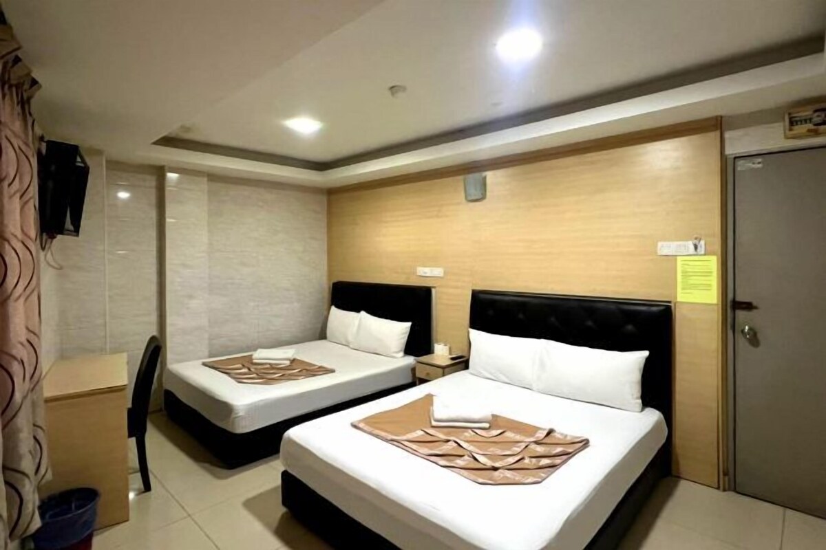 Quarto de hotel com duas camas, uma escrivaninha e um guarda-roupa.