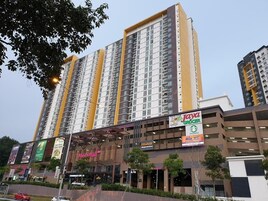 Um edifício alto com vários andares, cercado por estabelecimentos comerciais, incluindo um supermercado e uma farmácia.