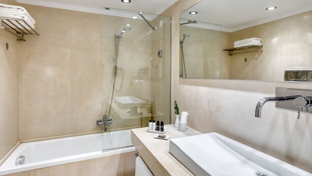 Uma casa de banho moderna com cabine de duche envidraçada, banheira e lavatório.