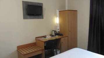 Quarto de hotel com uma cama, uma mesa com cadeira, uma televisão na parede e um guarda-roupa.
