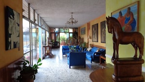 Um quarto amplo com uma grande janela, um candelabro e um conjunto de sofás azuis.