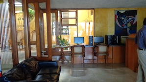 Um quarto com uma escrivaninha, duas cadeiras, um computador e um sofá.