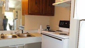 Cozinha compacta com armários de madeira, fogão branco e pia.