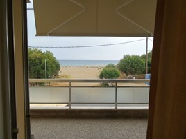 Vista de varanda com vista para uma praia, guarda-sóis e uma cerca.