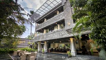 Um hotel com área de estar coberta ao ar livre, piscina e vegetação exuberante.