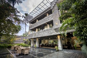 Um hotel com área de estar coberta ao ar livre, piscina e vegetação exuberante.