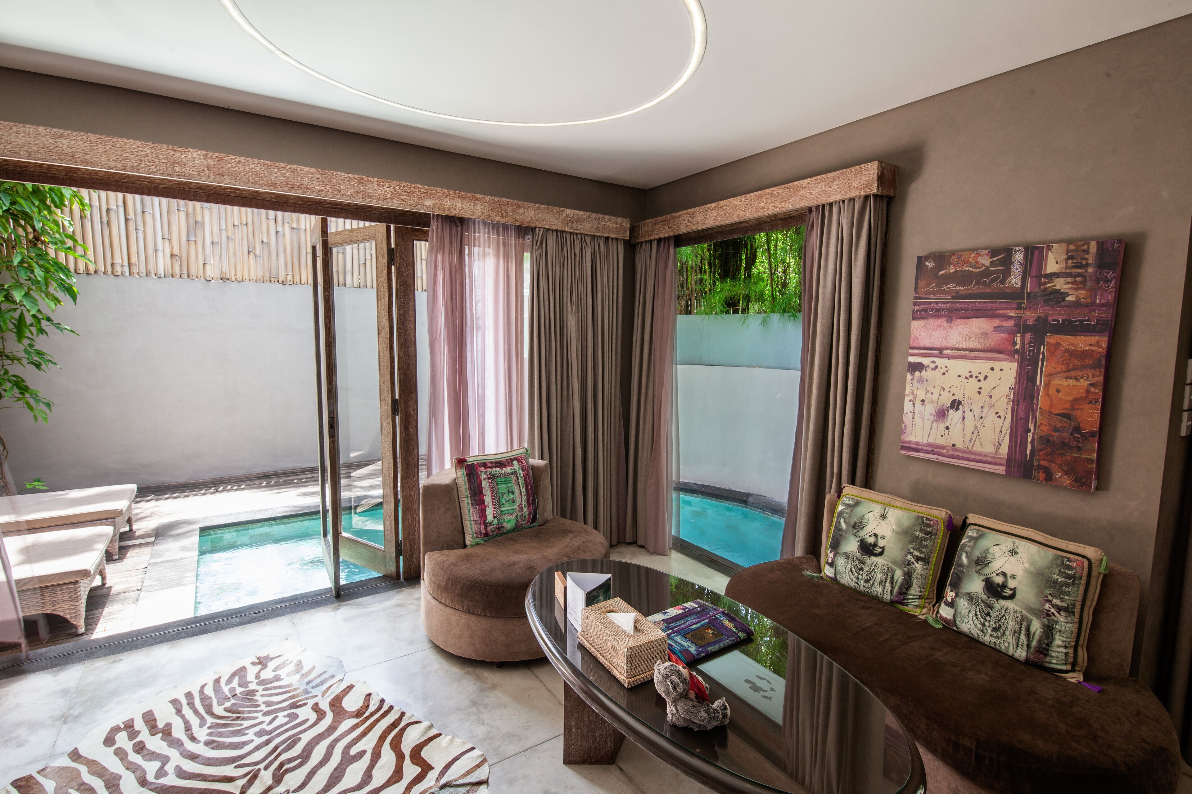 Uma sala de estar moderna com uma mesa de centro de vidro, assentos confortáveis e vista para uma piscina.