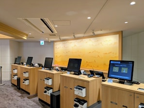 Uma área de recepção com vários computadores, uma parede com design texturizado e uma placa de sinalização.