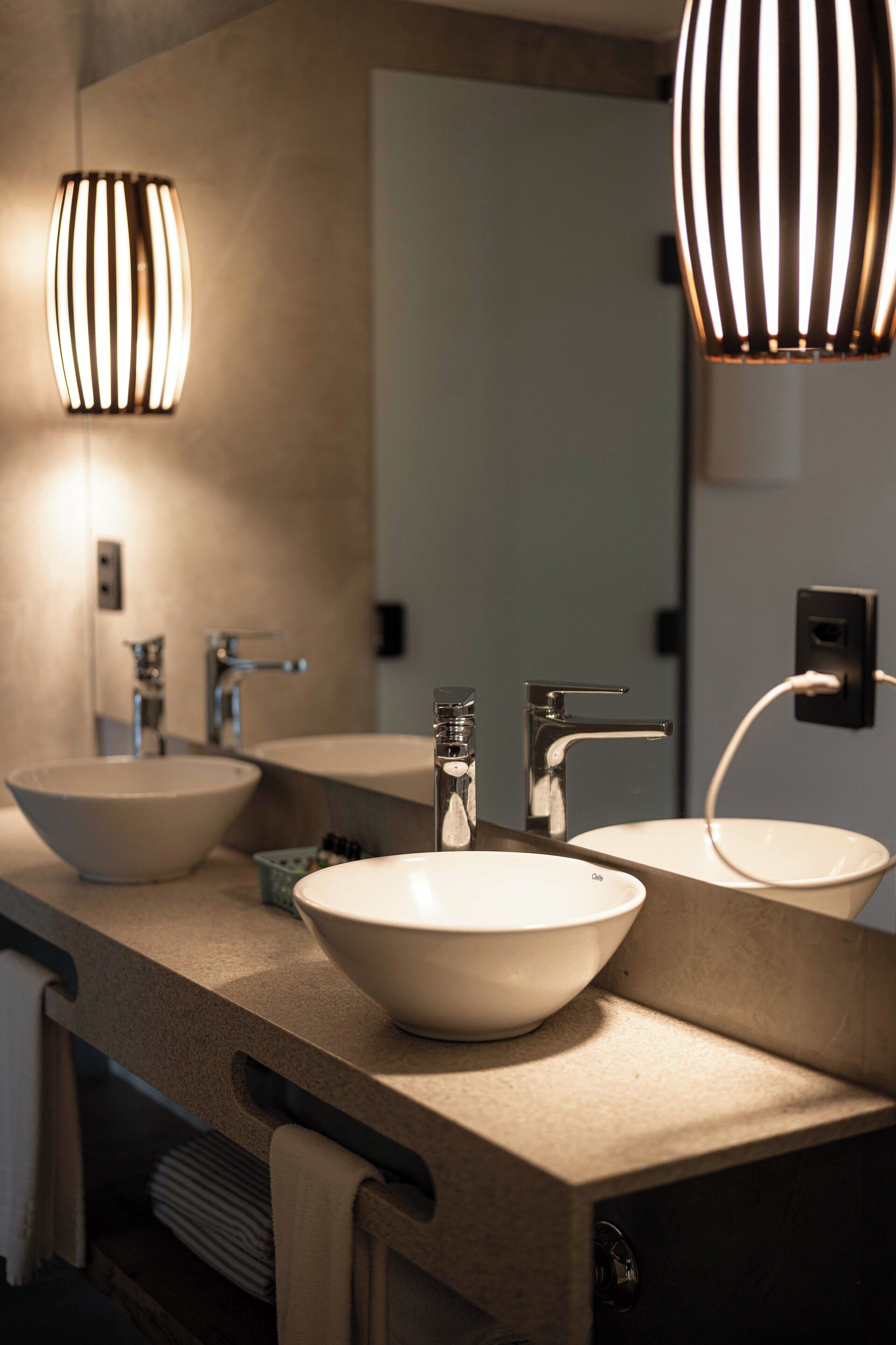 Uma casa de banho moderna com duas lavatórios, um espelho e duas luzes pendentes.