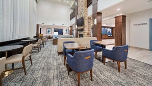 Um hall de hotel com áreas de estar, uma lareira e uma placa com a inscrição 'THE PANTRY'.