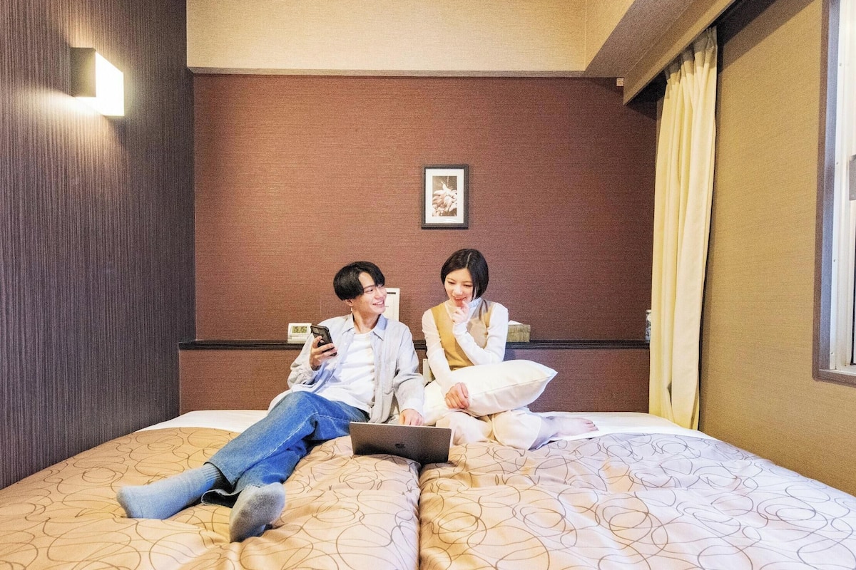 Quarto de hotel com cama, relógio de parede e quadro pendurado na parede.