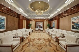 Uma sala de conferências com uma mesa comprida, várias cadeiras e um lustre.