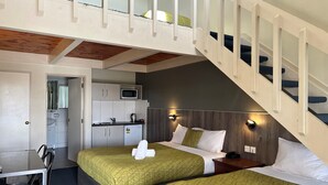 Quarto de hotel com duas camas, uma kitchenette e uma escada.