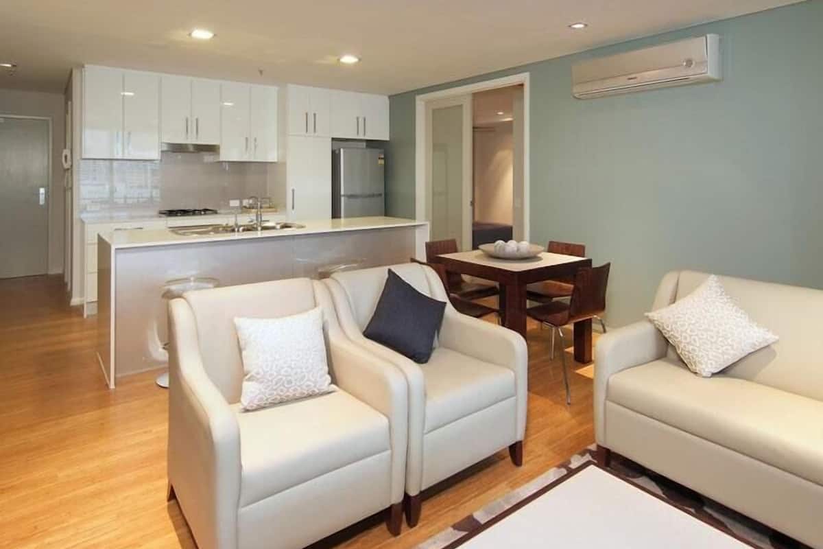 Um apartamento moderno com cozinha, sala de jantar e dois sofás.