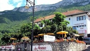 Restaurante chamado 'Les Acacias' com área externa e montanhas ao fundo.