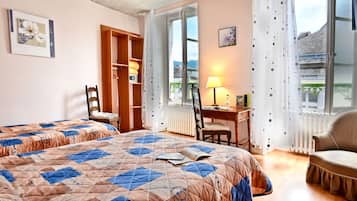 Quarto com duas camas, uma escrivaninha, uma cadeira e uma janela com cortinas.