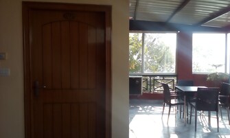 Quarto com porta de madeira, varanda com mesa e cadeiras, e janelas amplas.