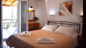 Quarto de hotel com cama, escrivaninha, cadeira e varanda.