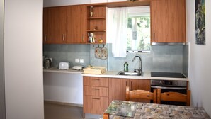 Uma cozinha compacta com armários de madeira, uma pia, uma torradeira e uma mesa com toalha de mesa florida.