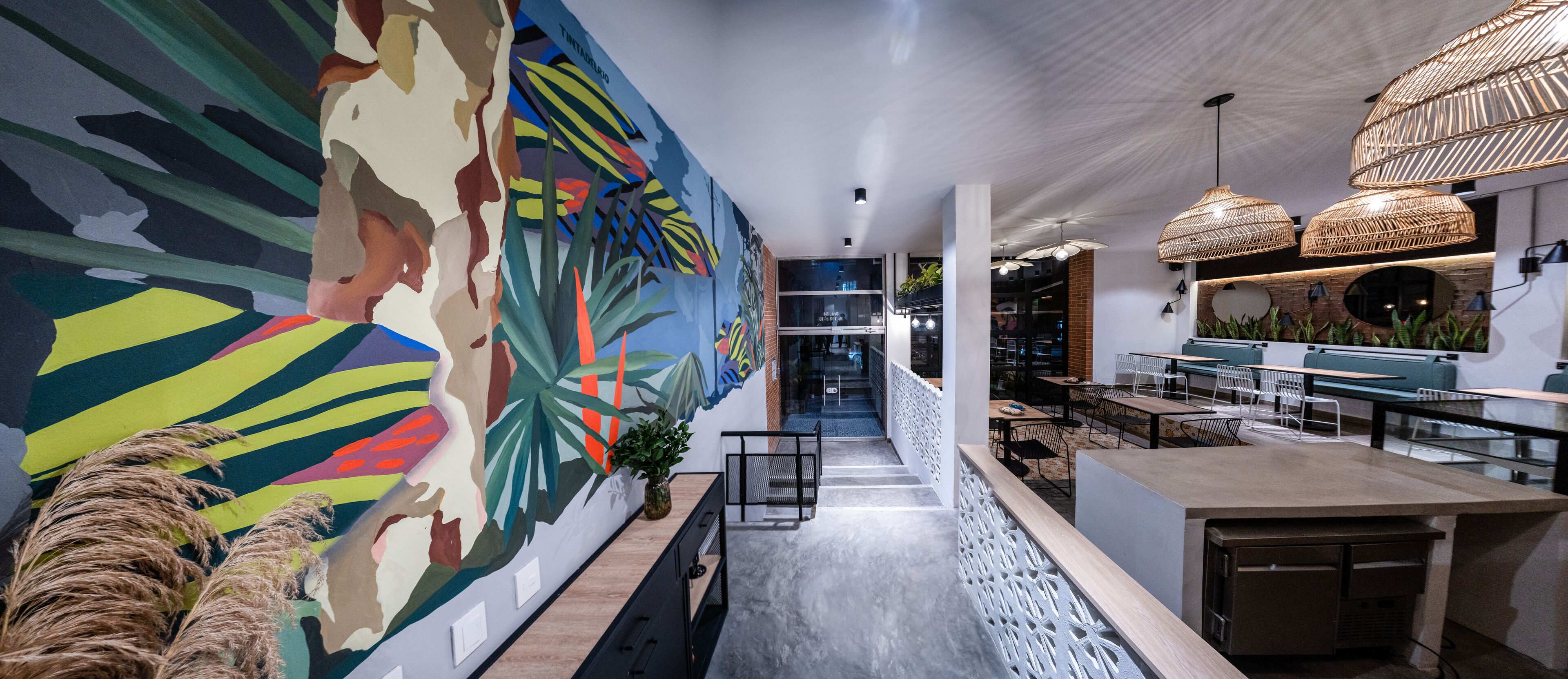 Interior moderno com um mural colorido, uma escada e uma área de estar com luminárias de vime.